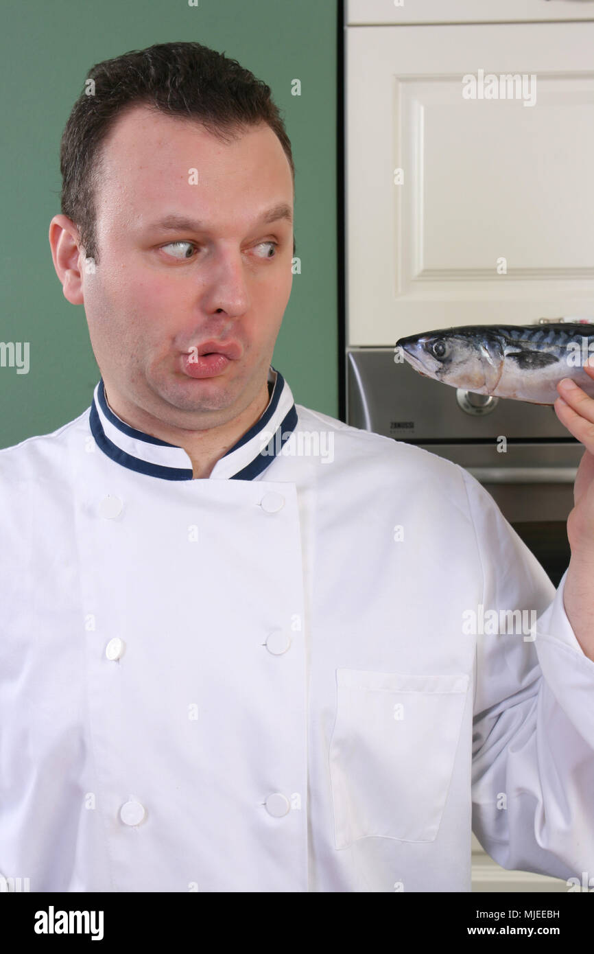 Chef is looking at head of frozen fish with question expression on his ...