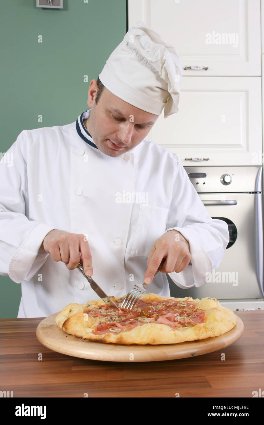 Chef is cutting pizza slice to try the taste of it Stock Photo - Alamy