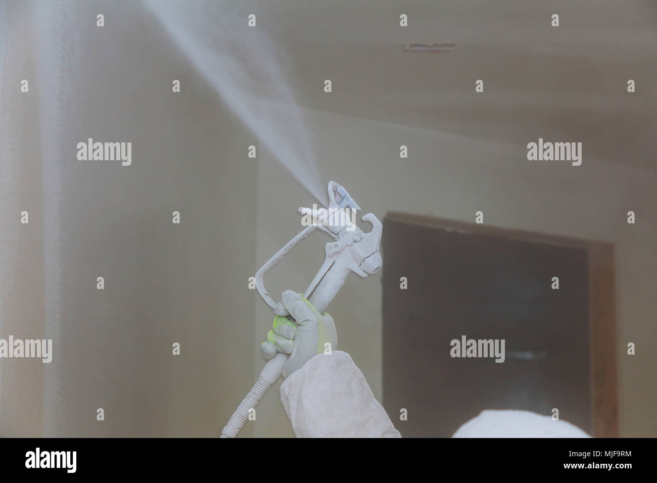 Worker painting wall with spray gun in white color. House Painter Spray ...