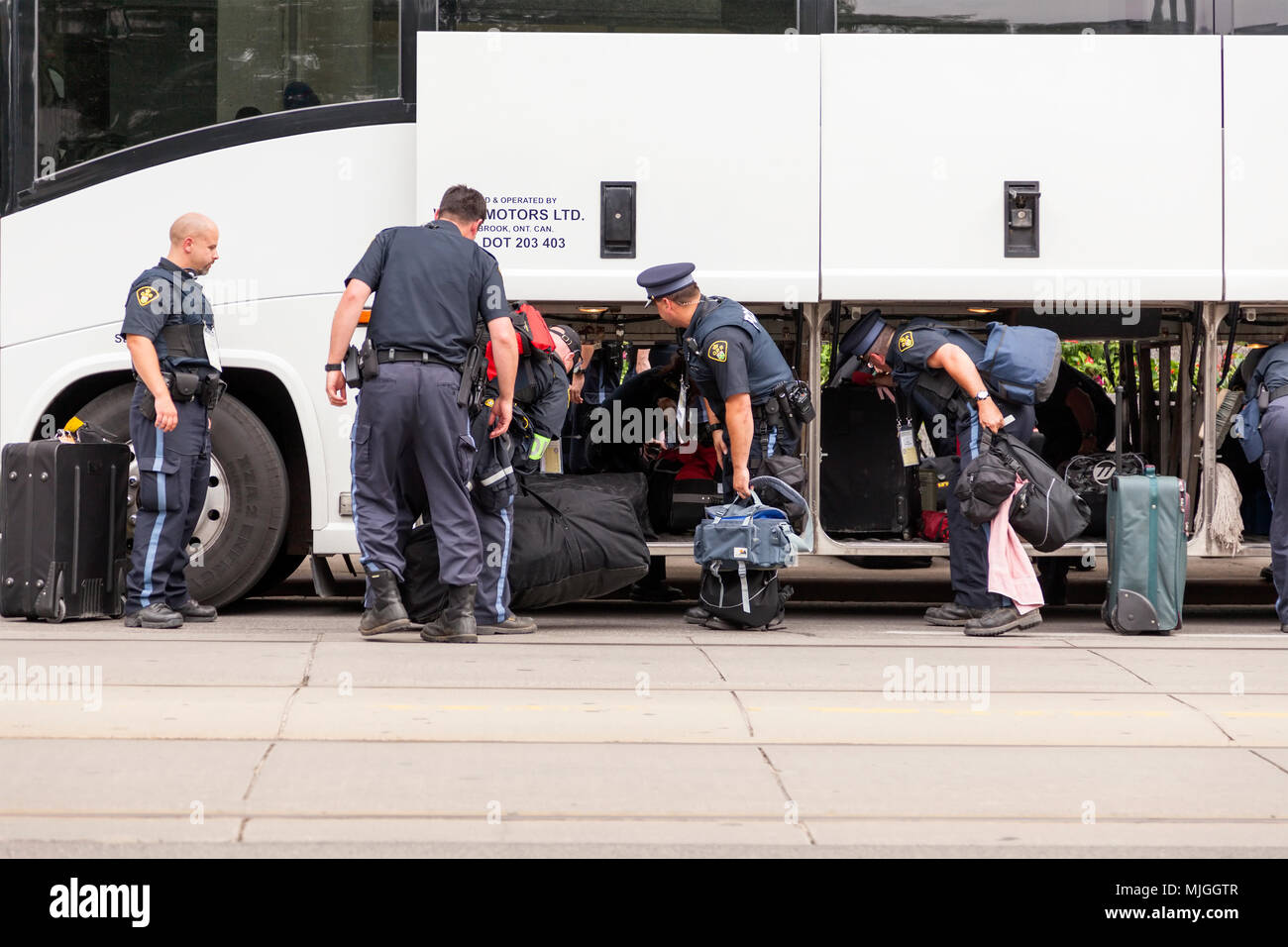 OPP (Ontario Provincial Police) officers unloading equipment from a bus ...