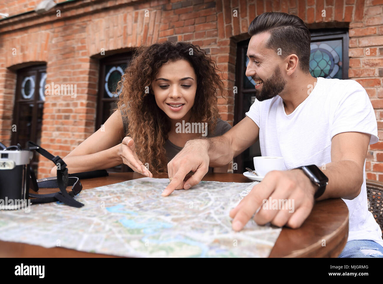 Young tourists drinking coffee at cafe and reading city map Stock Photo ...