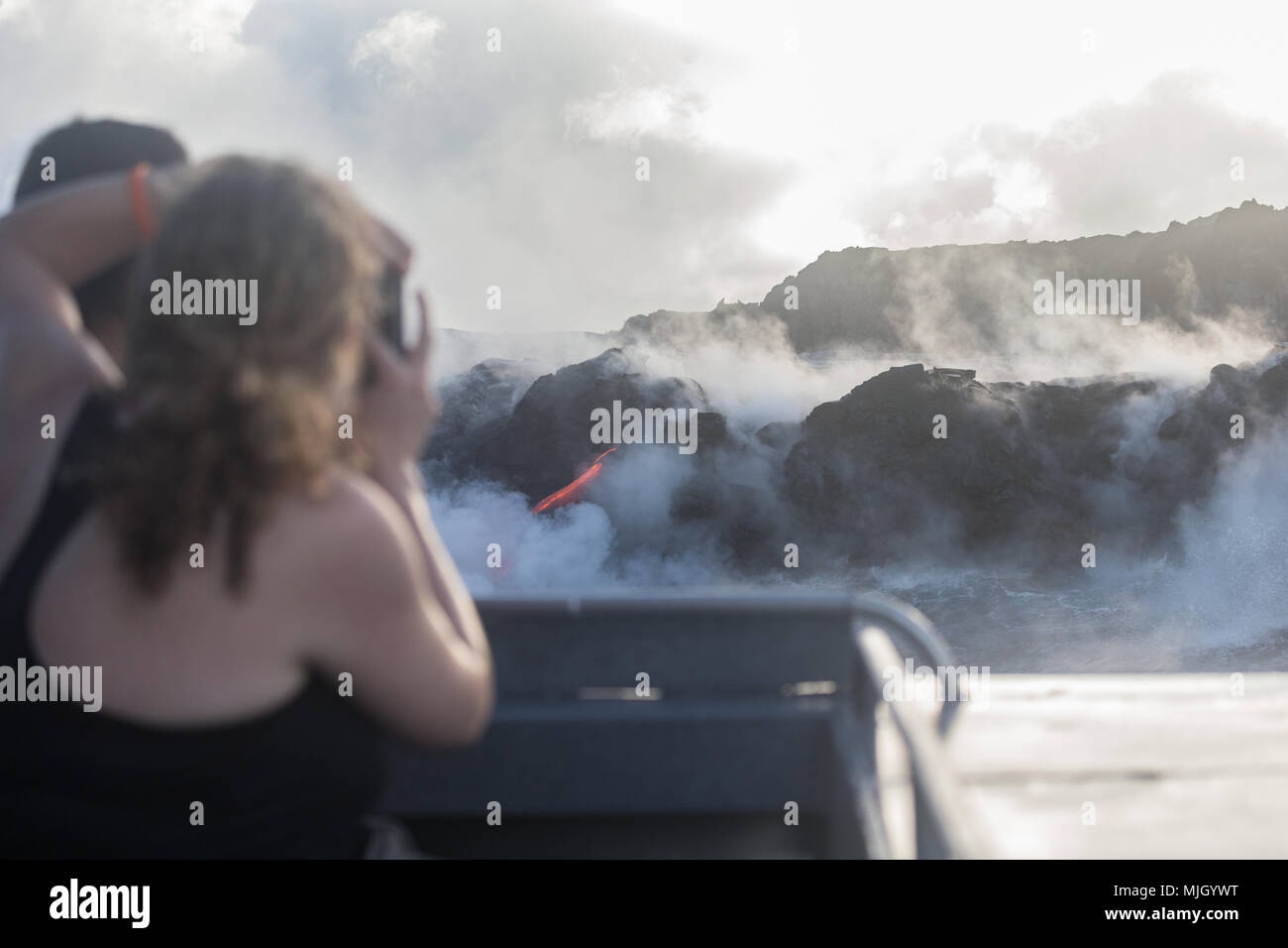 Visitors watch and photograph streams of lava pouring into the Pacific ...