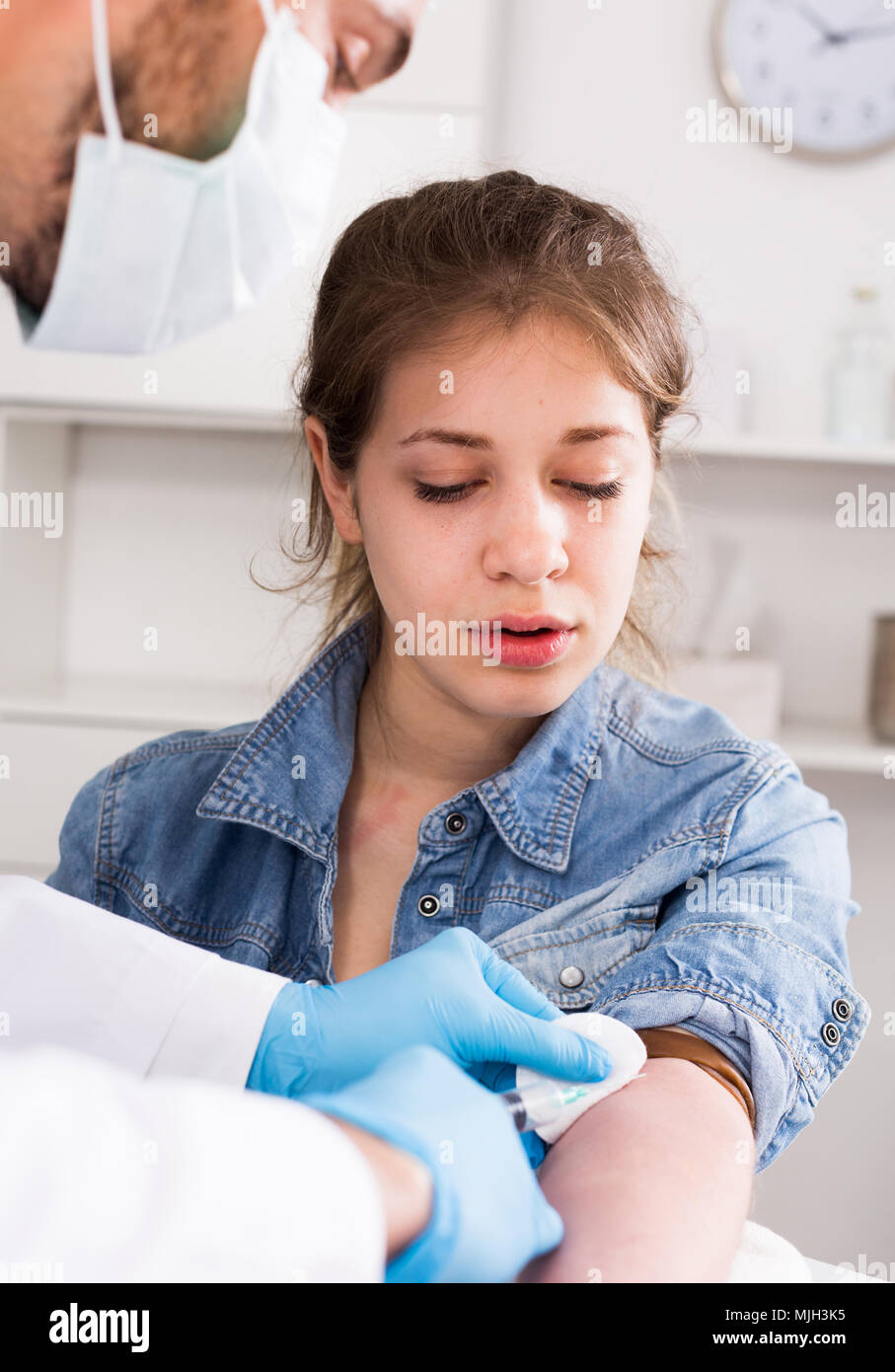 Male doctor using syringe to make injection to young patient in ...