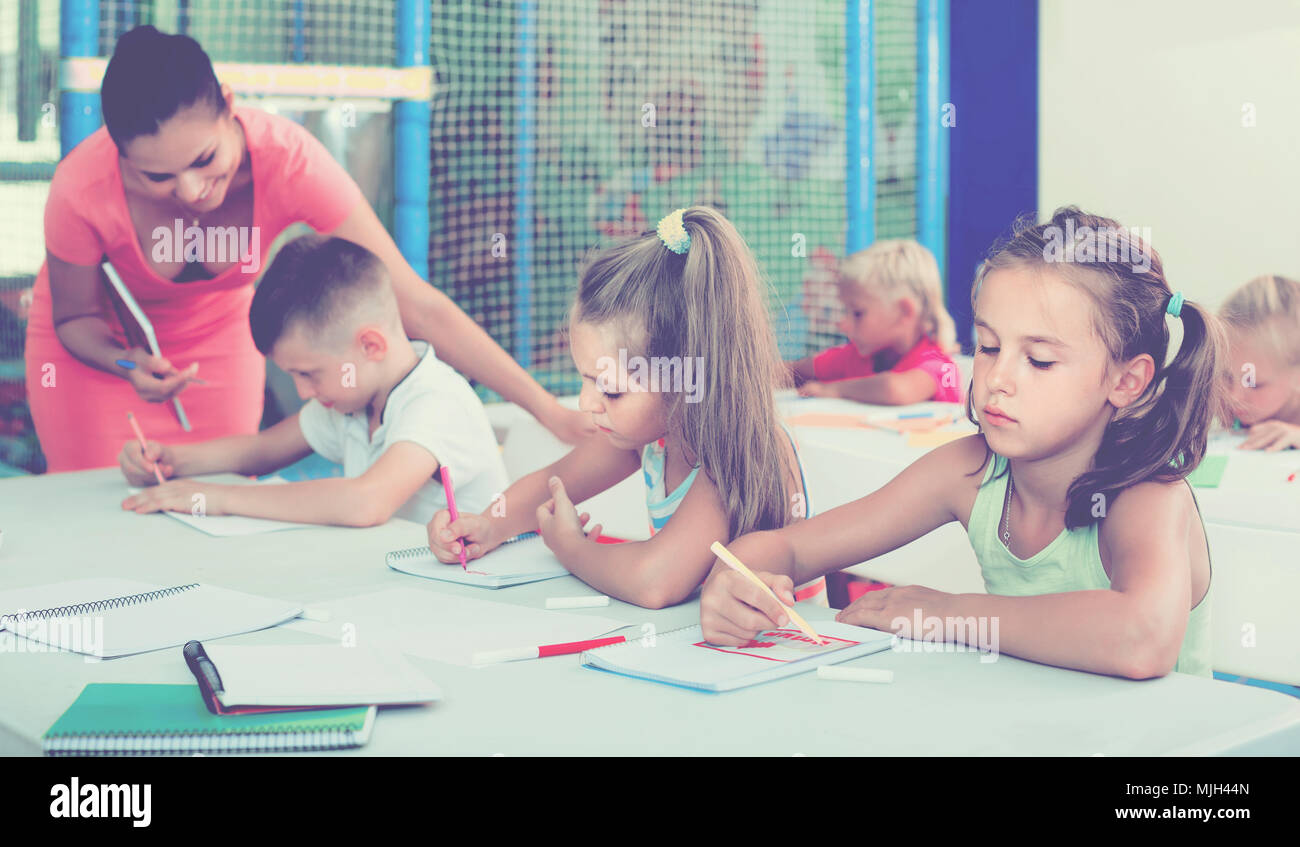 positive children sitting together and studying in class at school ...