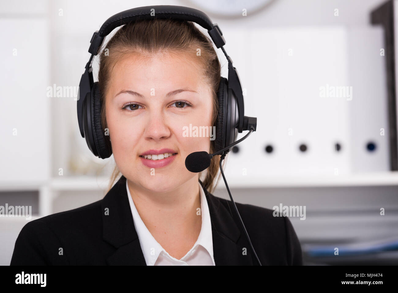 Portrait of young dispatcher in black suit which is talking by headset ...