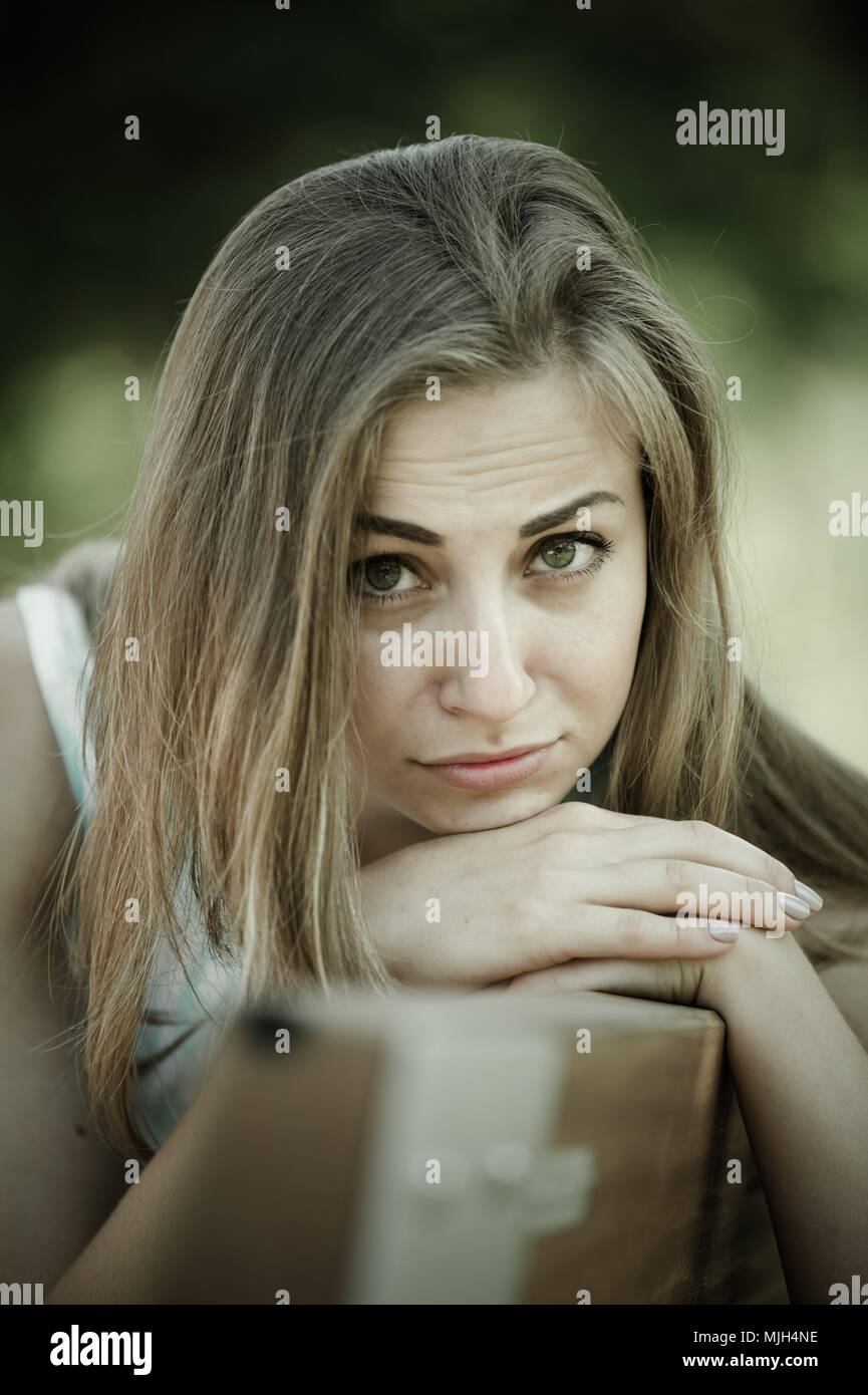 portrait of sad spanish girl sitting on bench outside in park Stock ...
