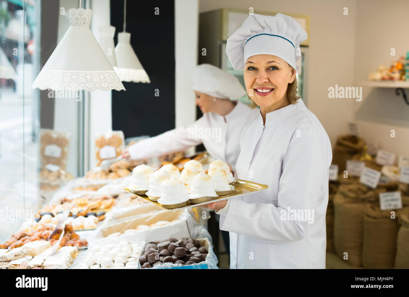 Portrait of adult female baker with pastry smiling in bakery Stock ...
