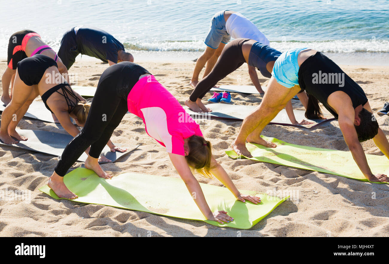 Yoga on beach, group of people practicing healthy lifestyle Stock Photo ...