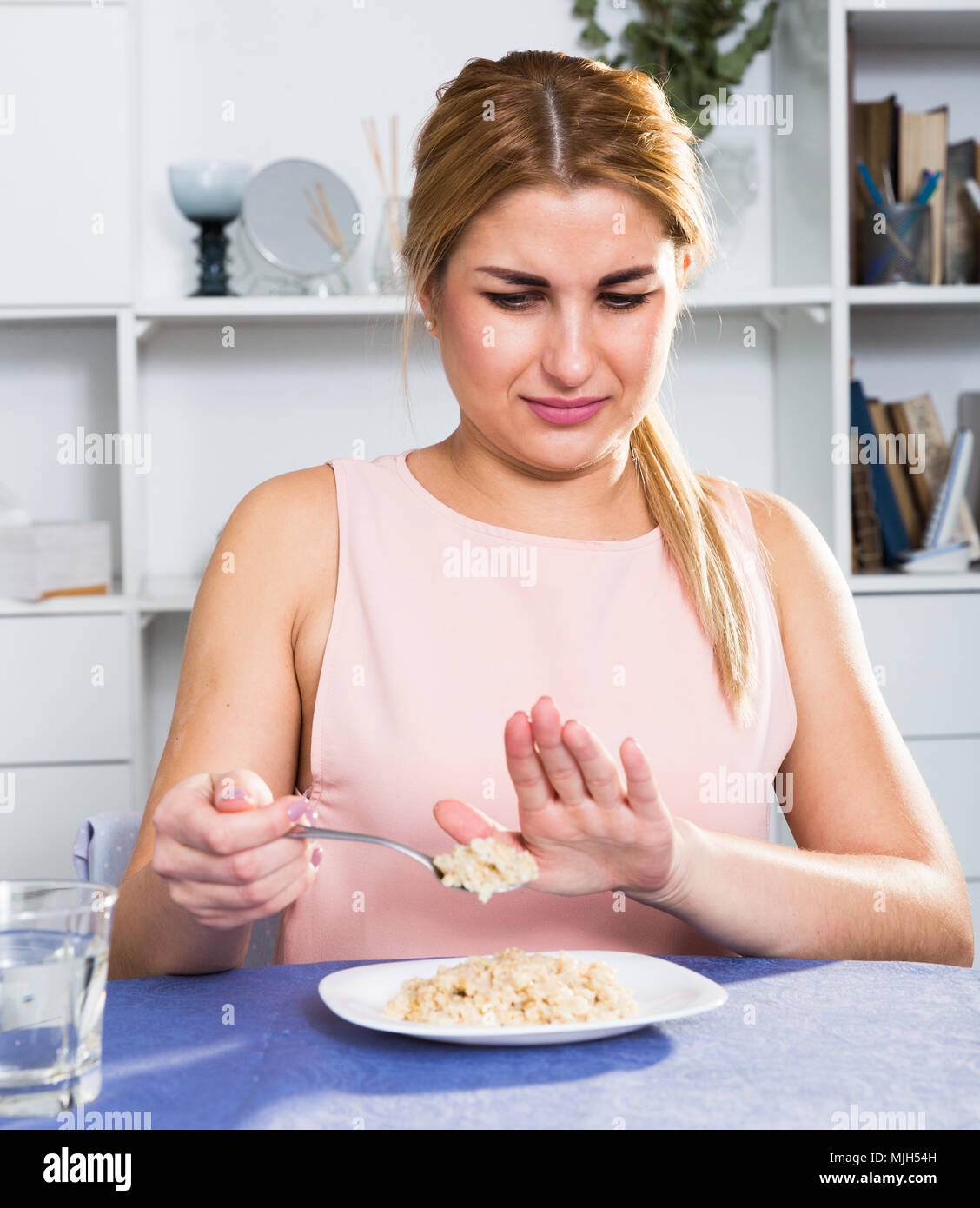 Female is dieting and disgusted eating oatmeal porridge at home Stock ...