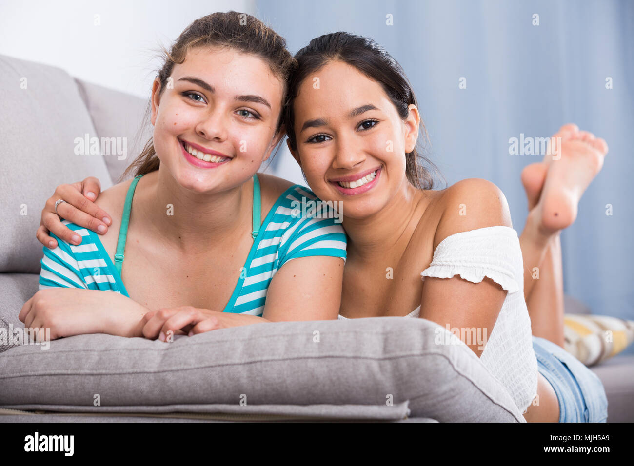 Cheerful teens girls spending time together, laughing on couch Stock ...