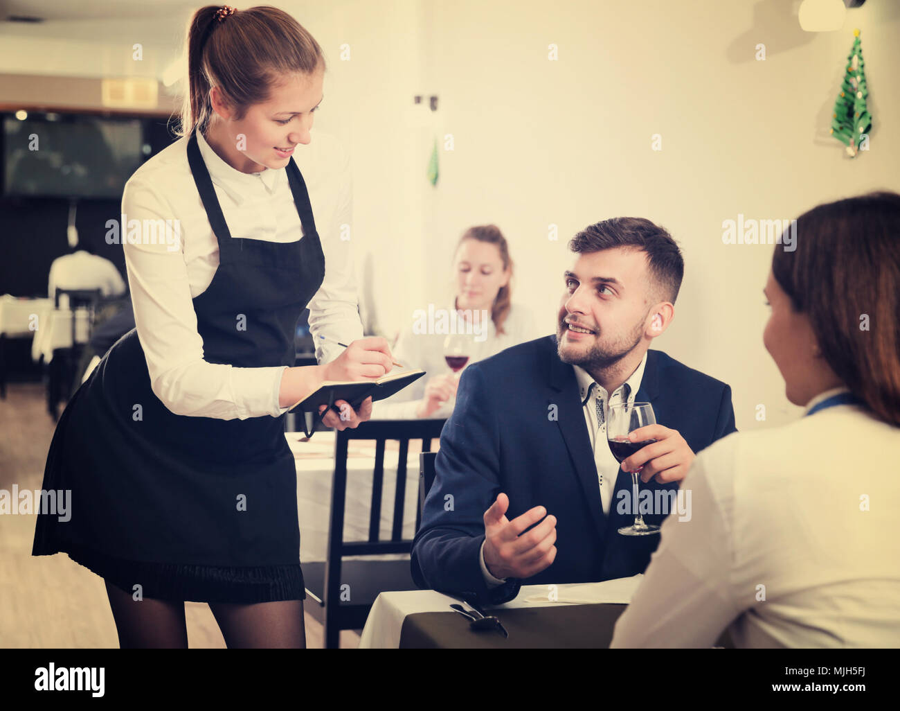 Couple is giving order to female waiter in luxury restaurante indoor ...