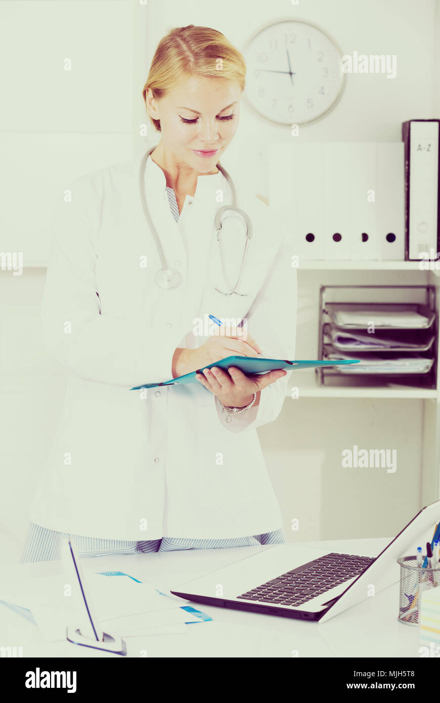 portrait of young spanish positive female medic with clipboard in ...