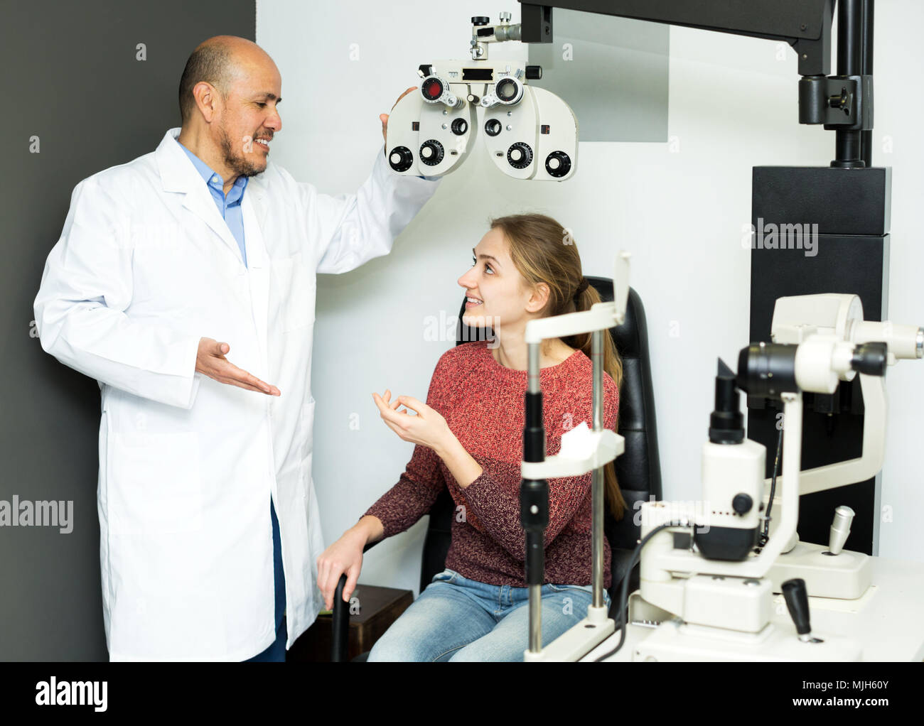 Elderly male optician doing eye check up to smiling girl Stock Photo ...