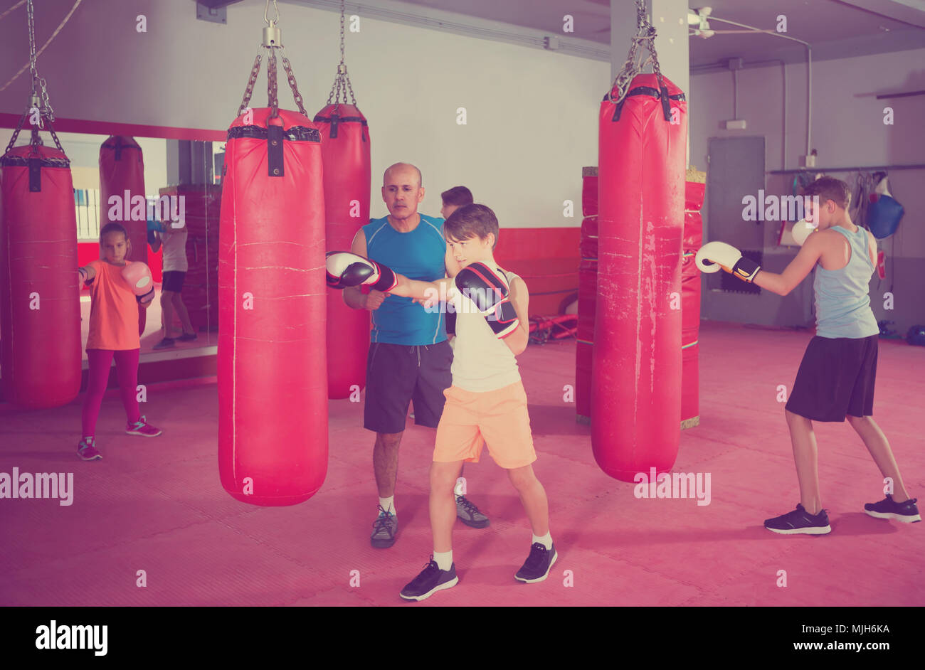 Children practice punching with instructor in a boxing training session ...