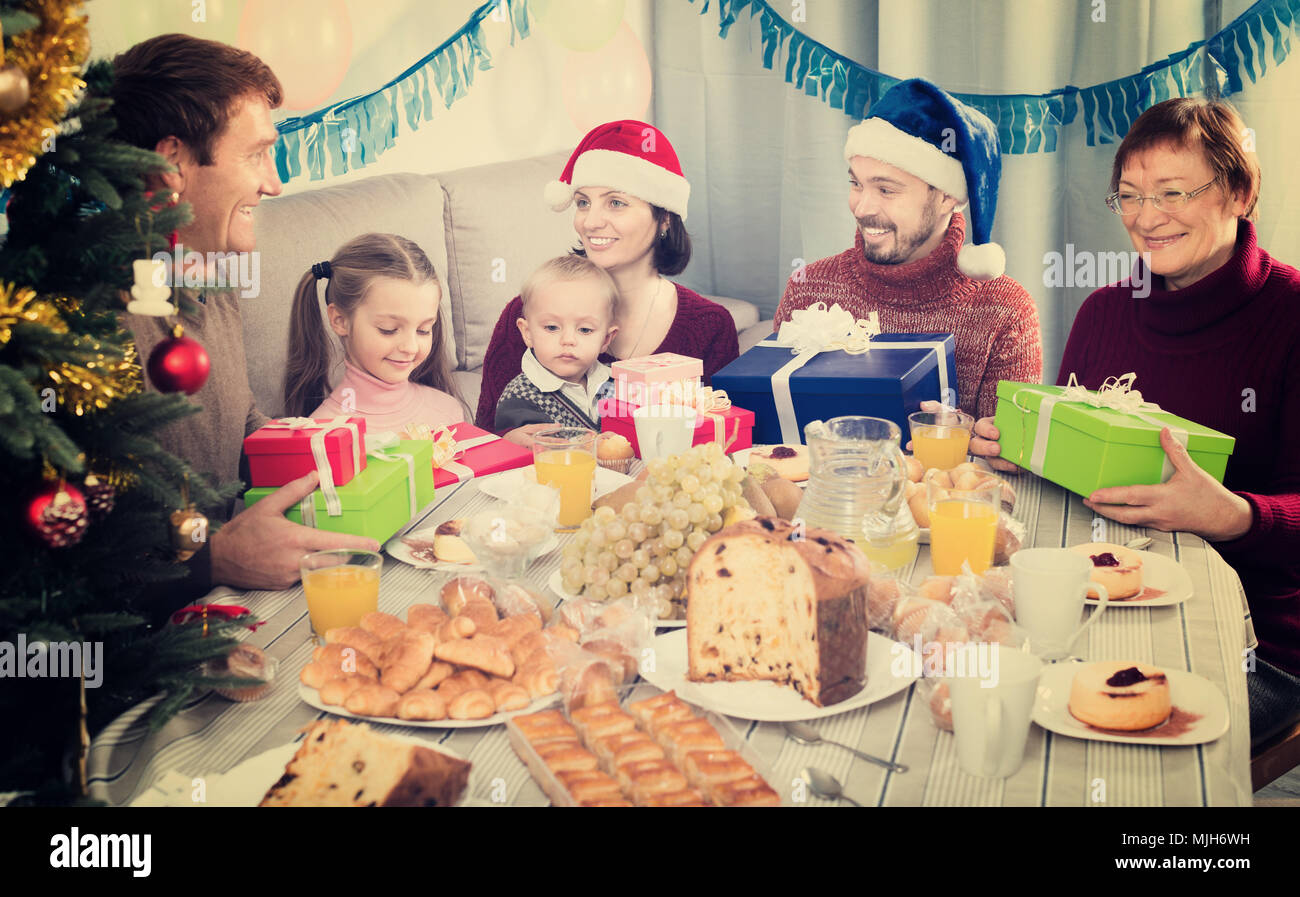 Family members handing gifts to each other during Christmas dinner ...