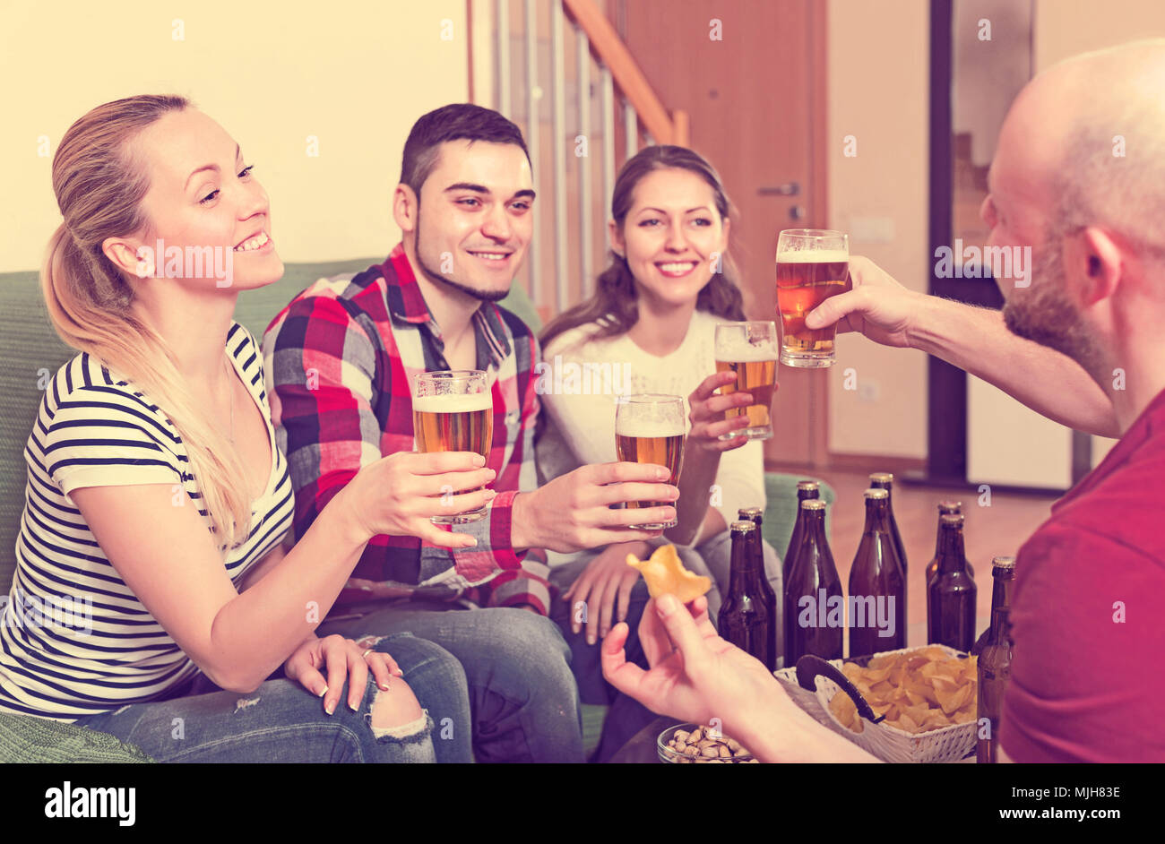 Two happy couples hanging out with beer and snacks at at house party ...