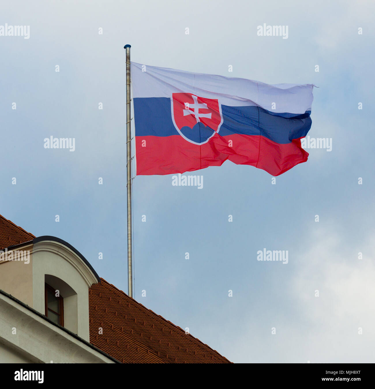 Image of national flag of slovakia waving against blue sky at roof ...