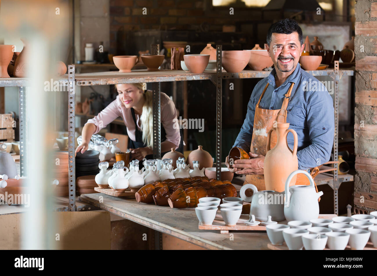 Smiling man and woman potters working in pottery workshop Stock Photo ...