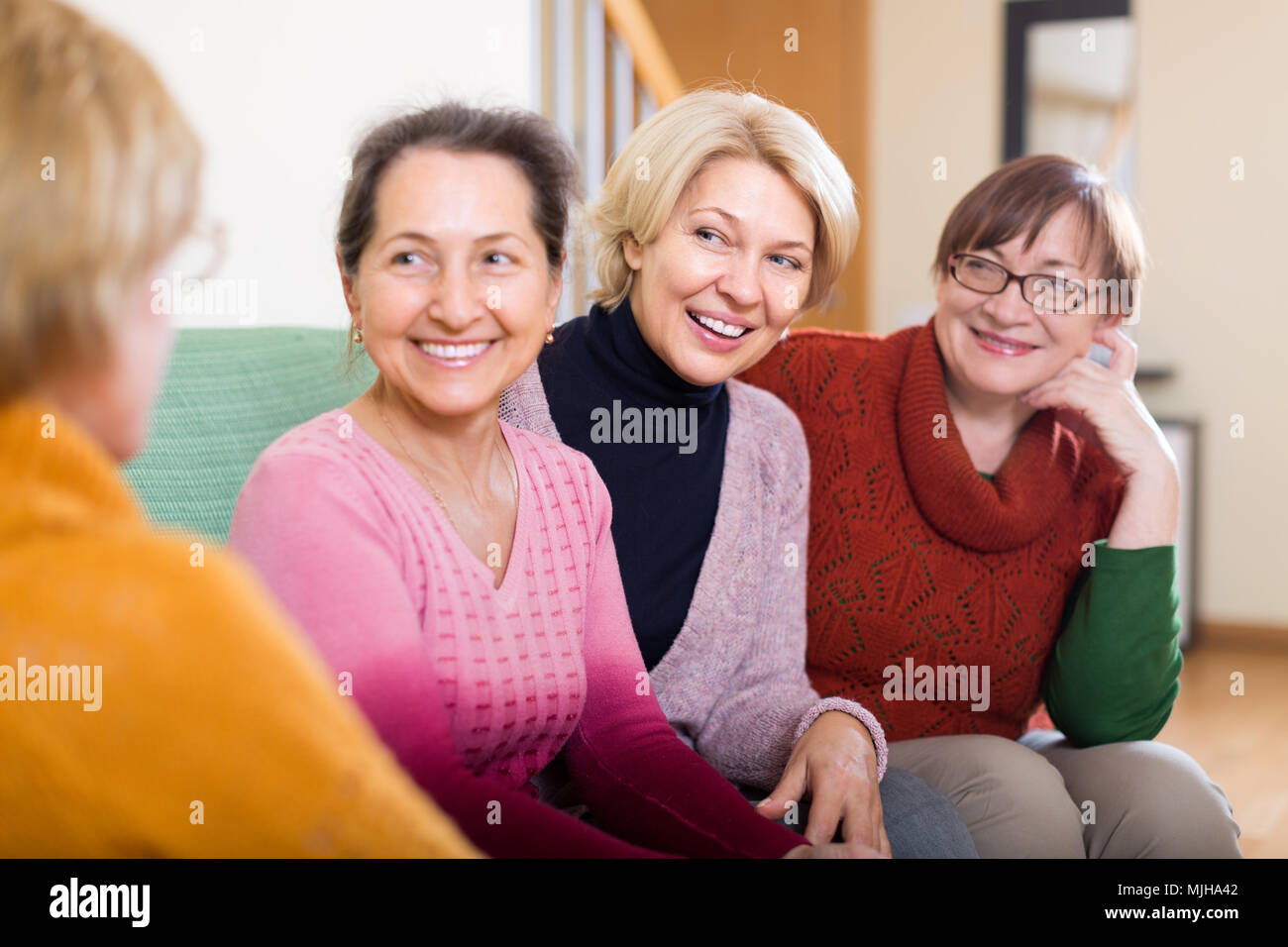 Smiling senior women sitting on sofa and talking. Focus on blonde Stock ...