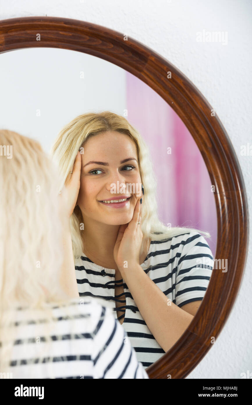 Young woman looking in mirror after waking up Stock Photo - Alamy