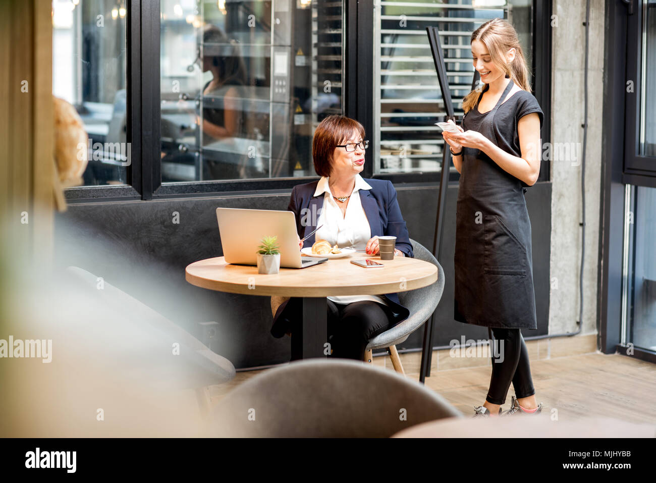 Smiling waitress sitting table hi-res stock photography and images - Alamy