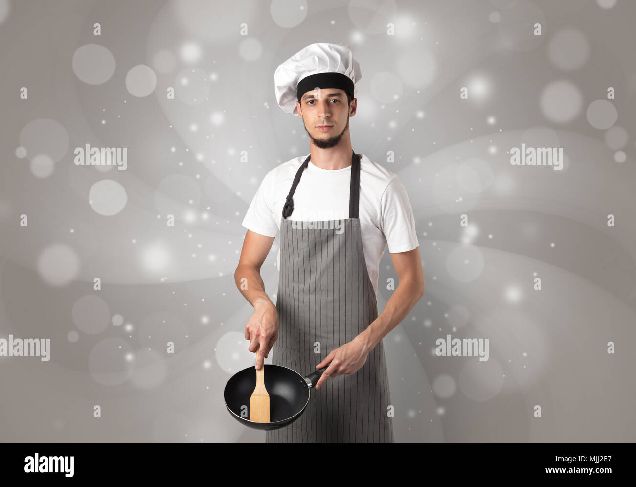 Male cook with kitchen tools and shiny grey wallpaper Stock Photo - Alamy