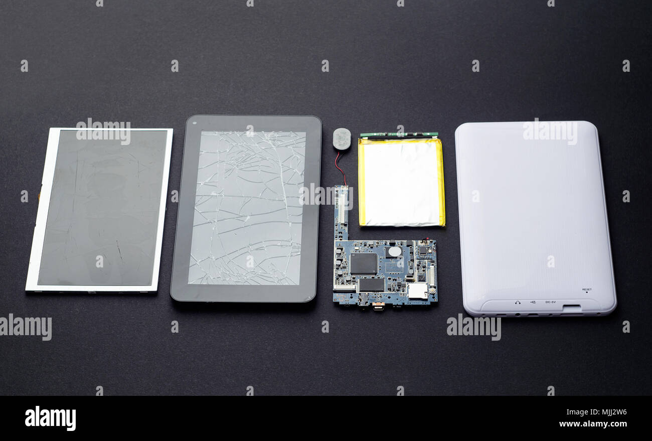 Components of a broken tablet organized over black background, top view ...