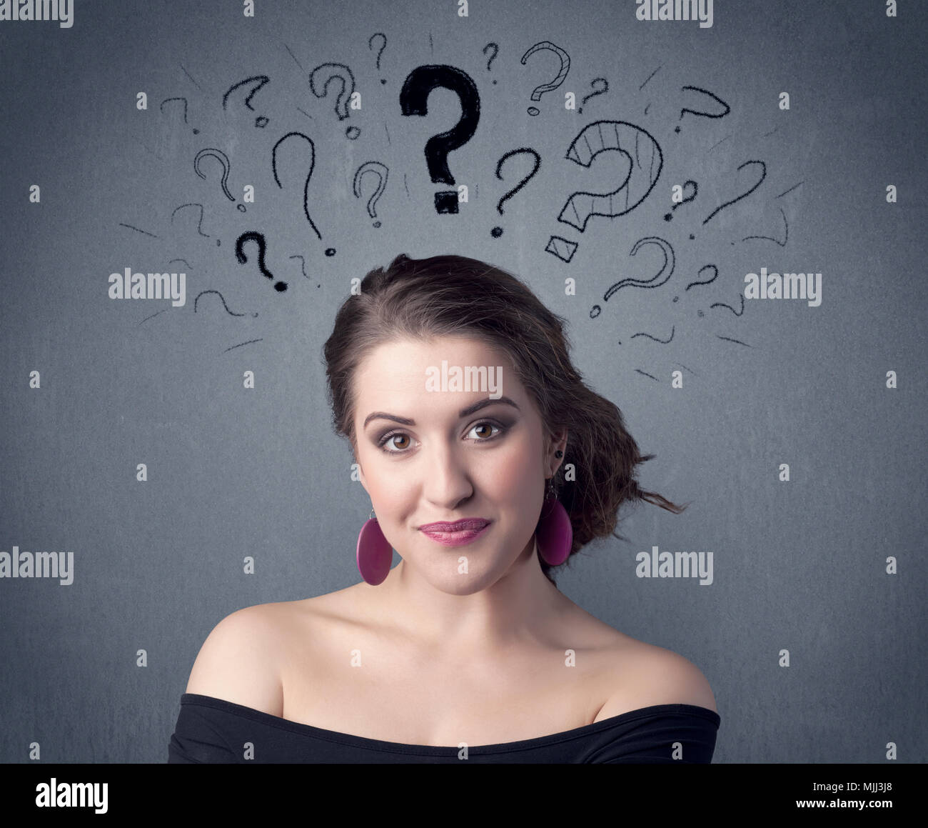 A pretty teenage girl standing confused in front of grey wall background with drawn question ...