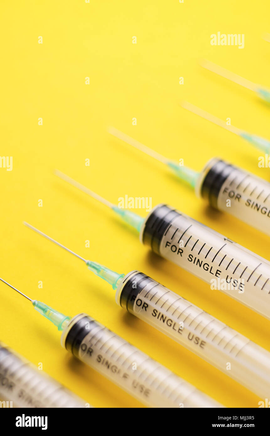Details of syringes with "for single use" text over bright yellow ...