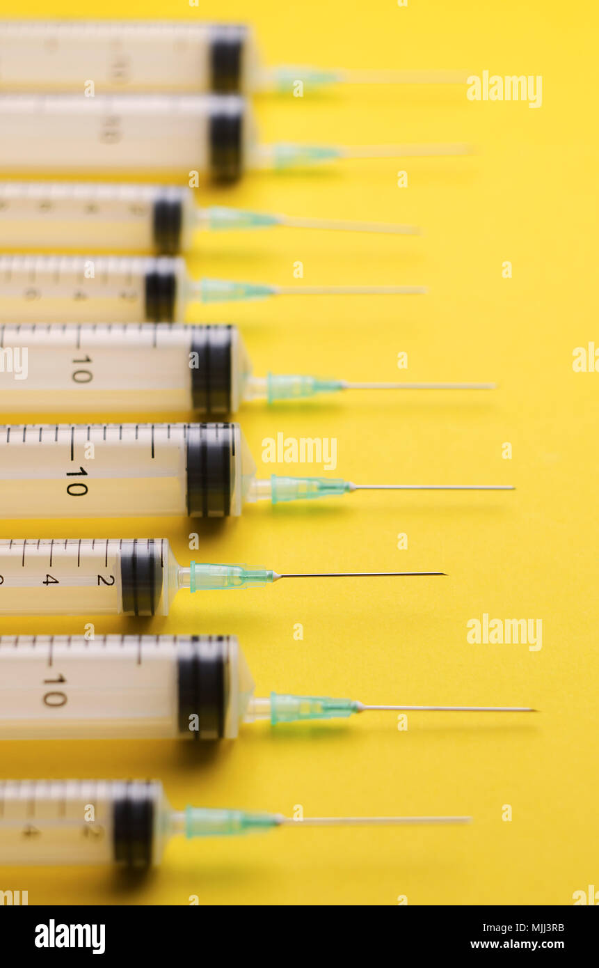 Details of syringes over bright yellow background Stock Photo - Alamy
