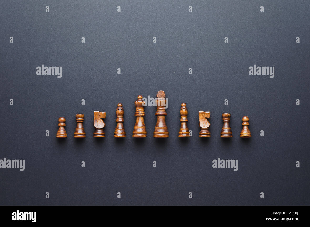 Wooden chess figurines organized in a row over black background Stock ...