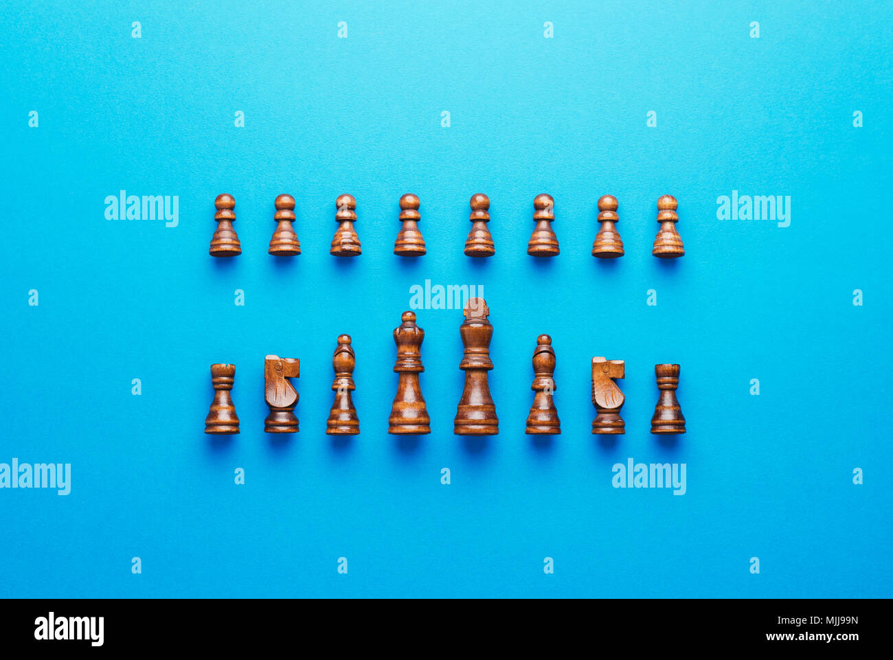 Wooden chess figurines organized in a row over blue background Stock ...