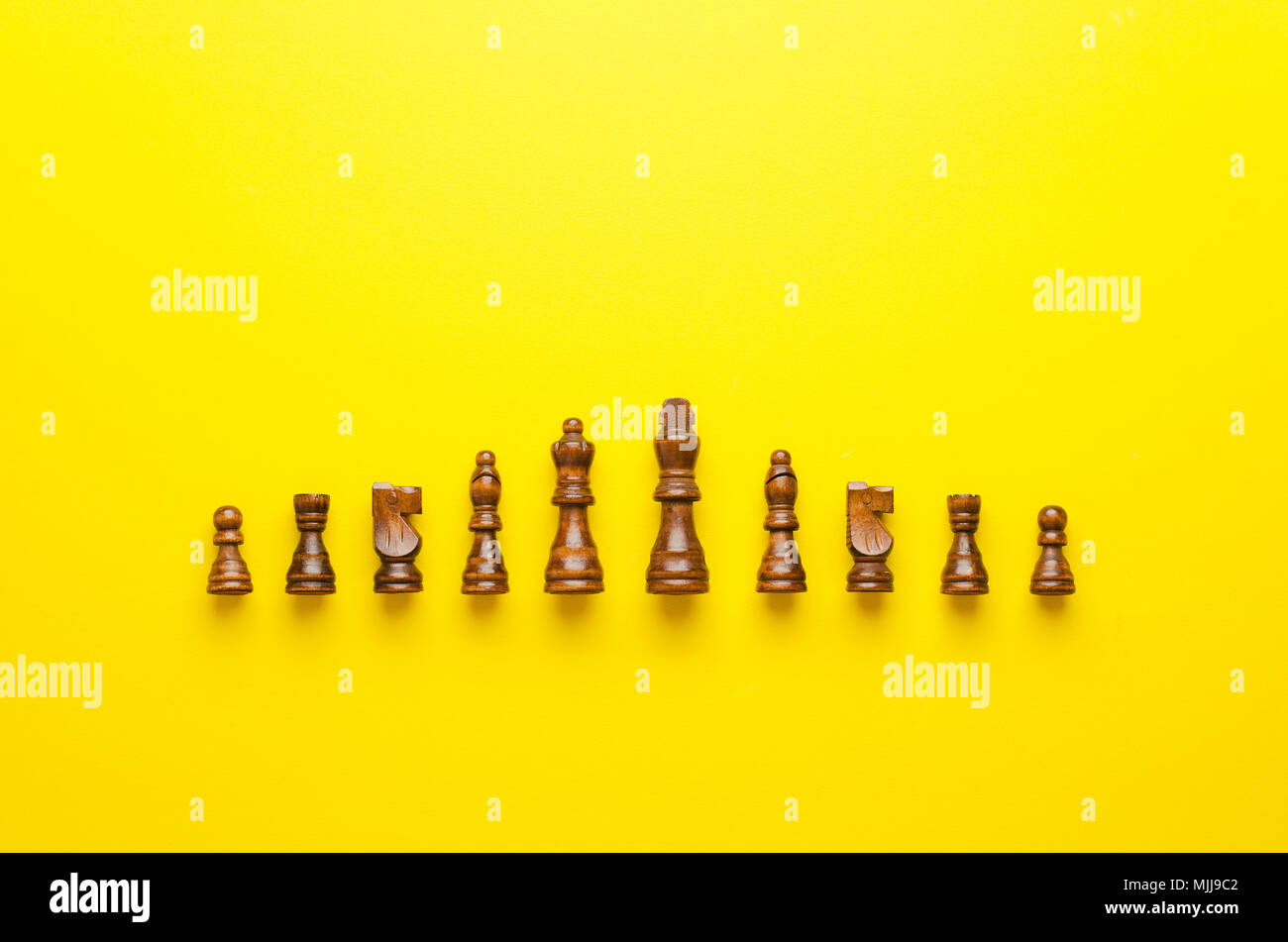 Wooden chess figurines organized in a row over yellow background Stock ...
