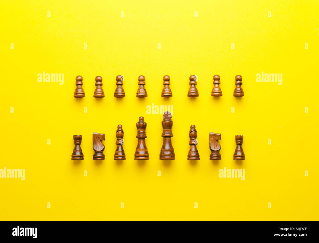 Wooden chess figurines organized in a row over yellow background Stock ...