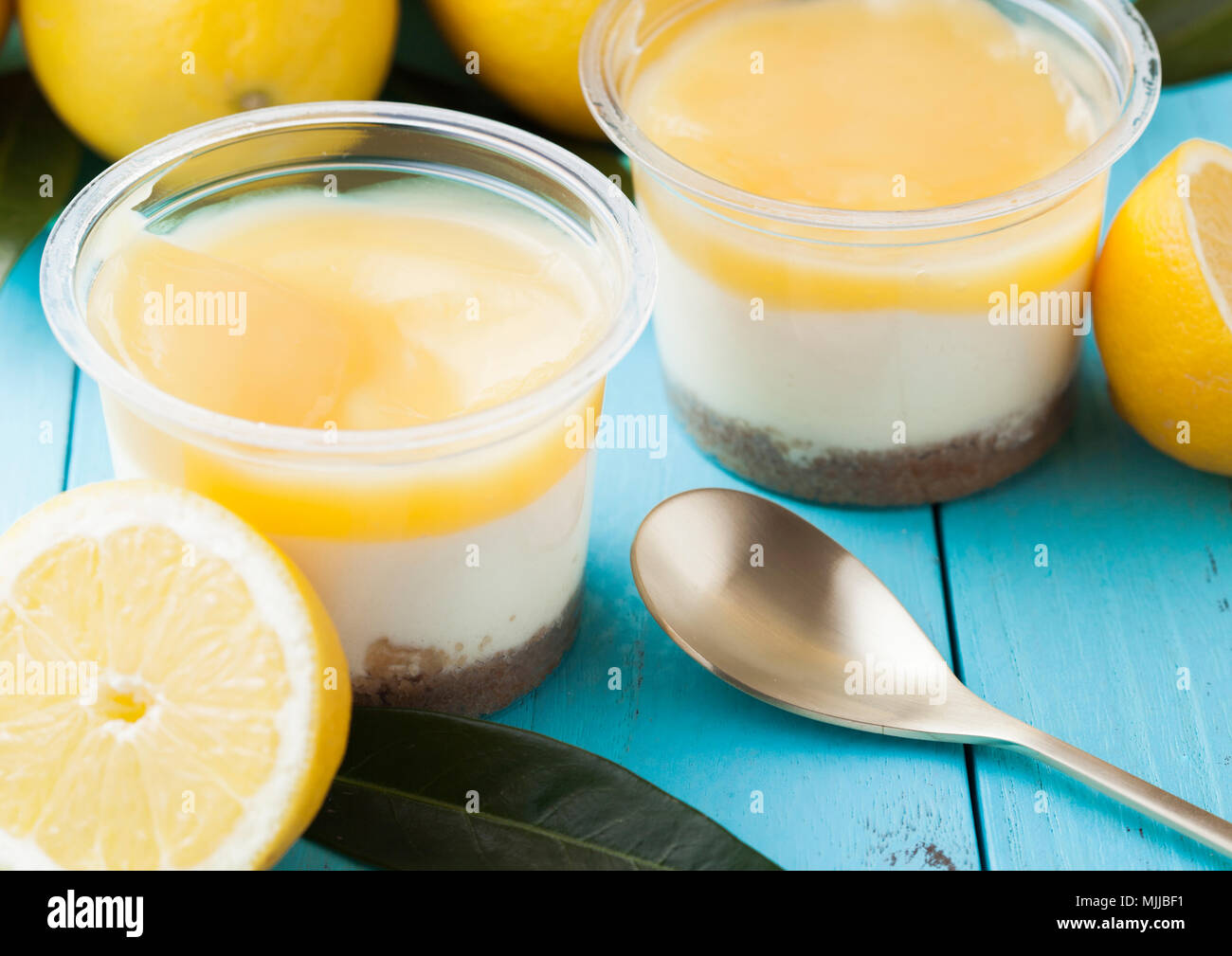 Plastic cups with lemon cream and biscuit dessert with raw lemons on ...
