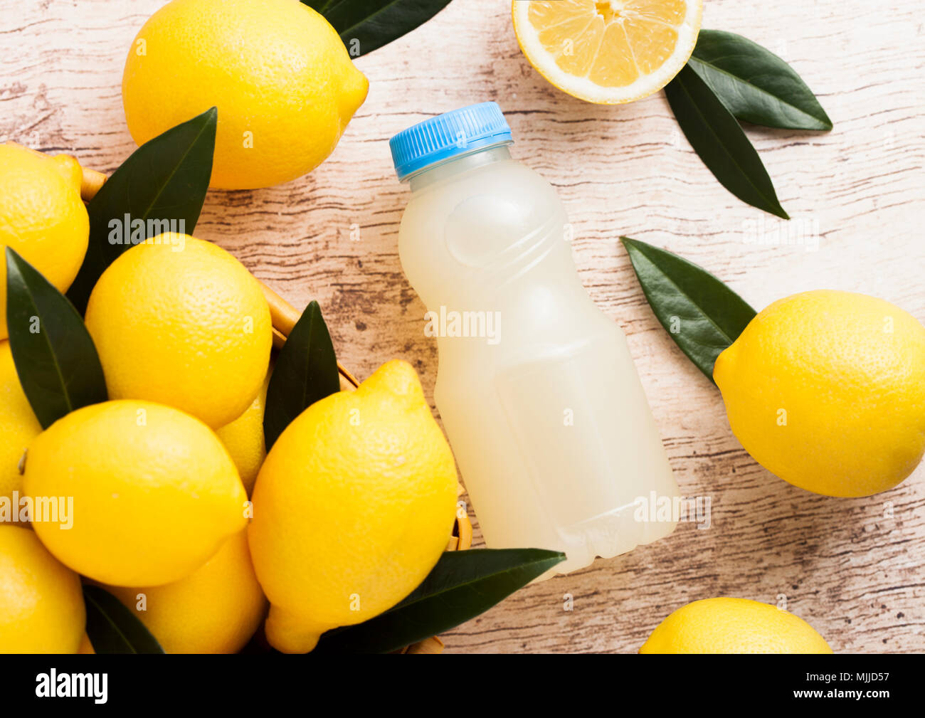 Plastic bottle of organic fresh lemon juice with raw lemons on light ...