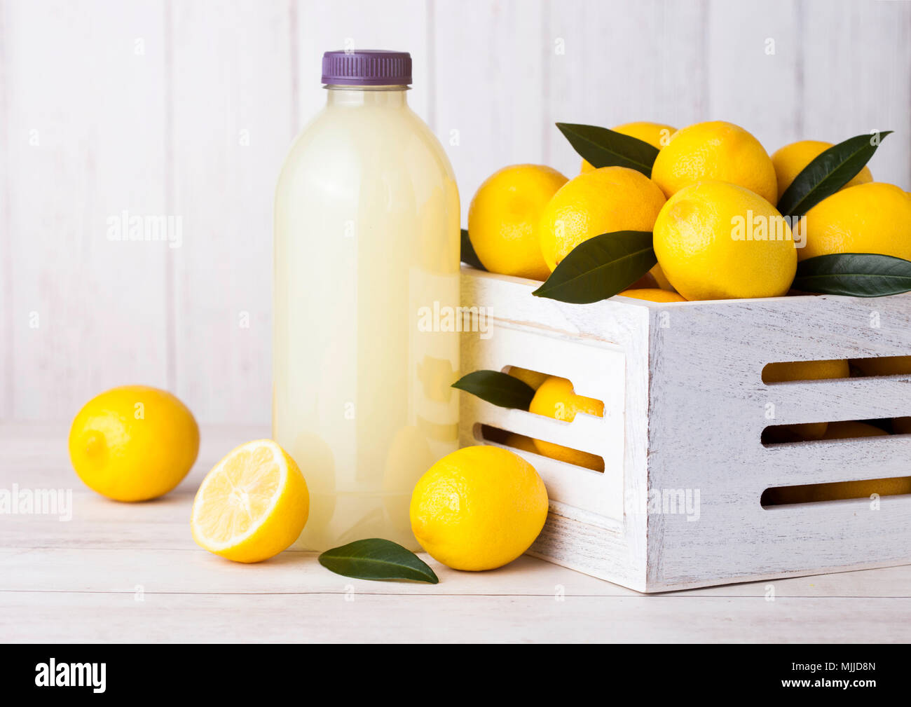 Plastic bottle of organic fresh lemon juice with raw lemons in white ...