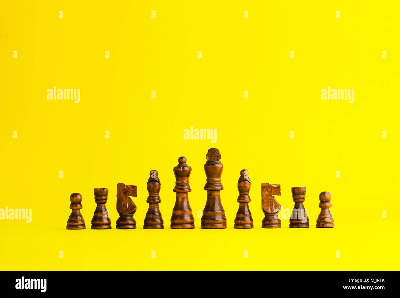 Wooden chess figurines organized in a row over yellow, background Stock ...