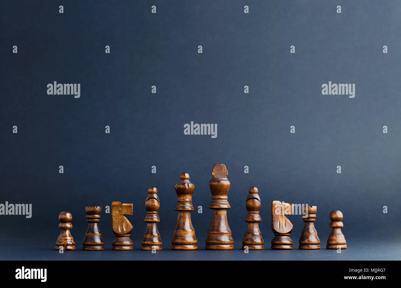 Wooden chess figurines organized in a row over black background Stock ...