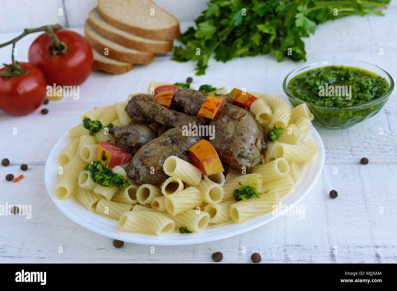 Pasta and fried goose liver (chicken, duck) with pesto and tomato on a ...