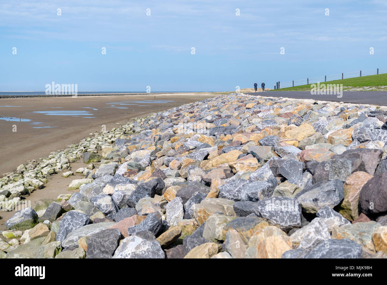 Wadden Sea dike with large colorful natural stone pebbles and cycle ...
