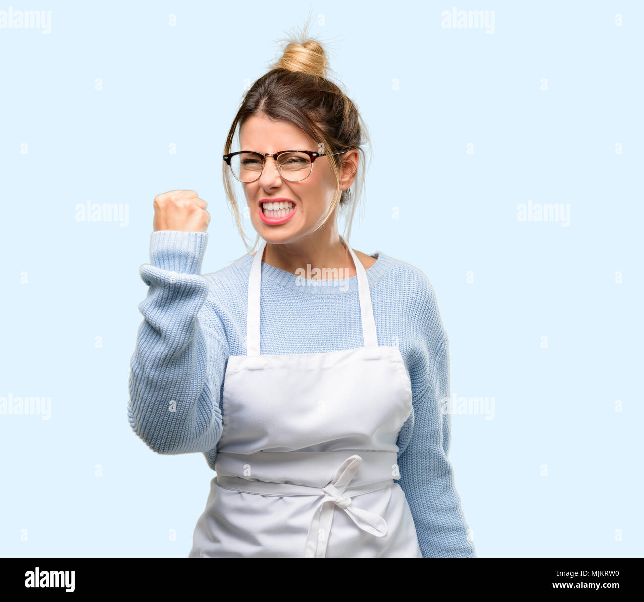 Young woman shop owner, wearing apron irritated and angry expressing ...