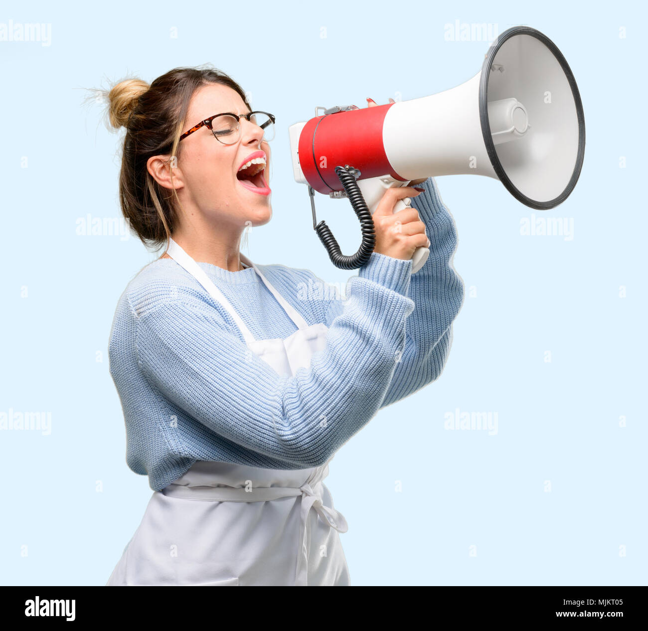 Young woman shop owner, wearing apron communicates shouting loud ...