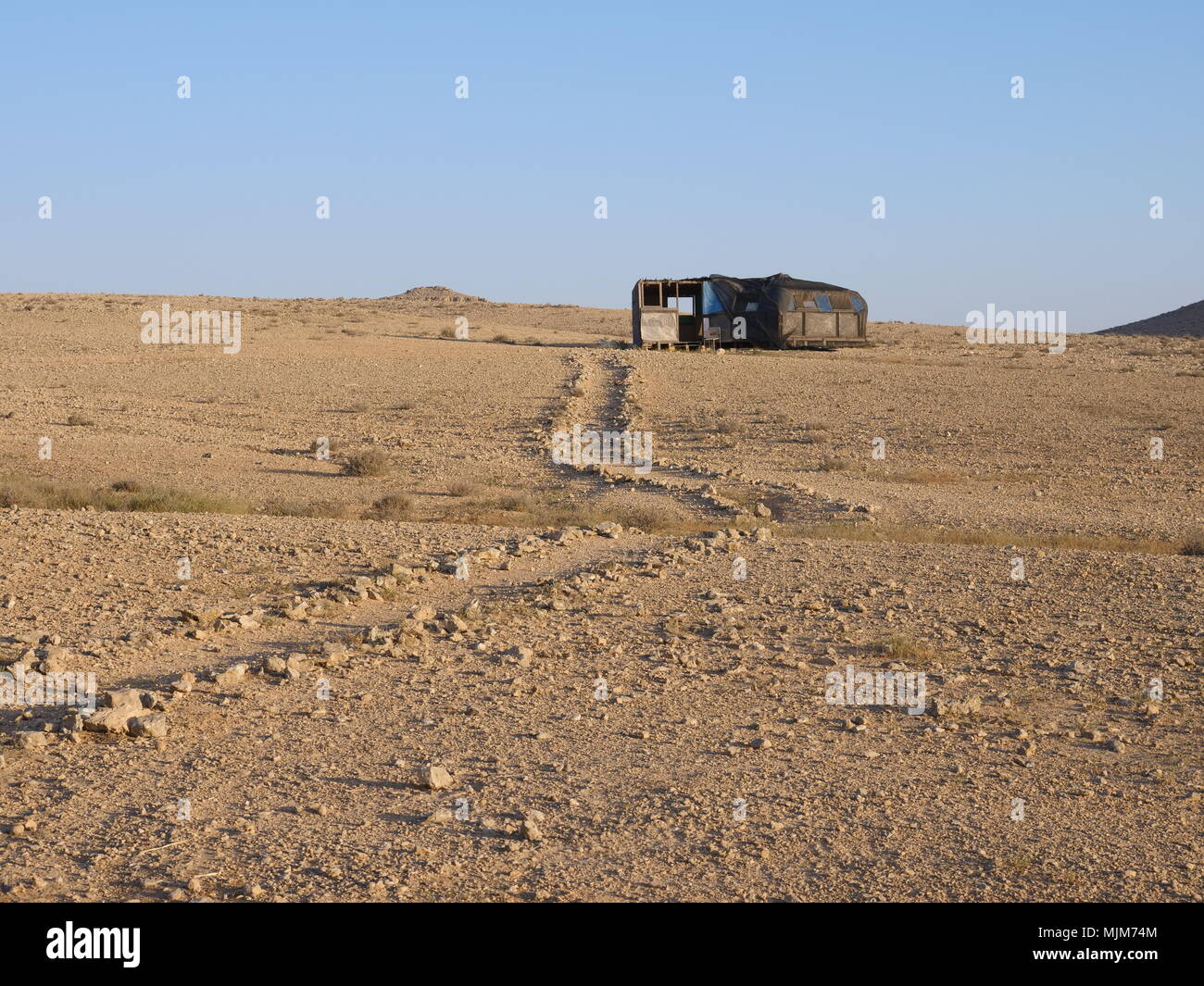Abandoned booth in desert viewed from the distance. Curvy trace or path ...