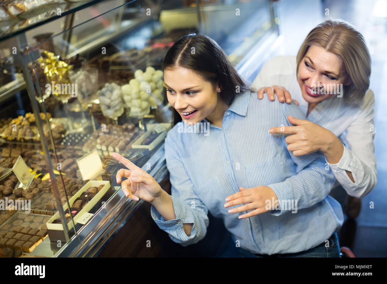Happy european women buying dark and white chocolate filled candies ...
