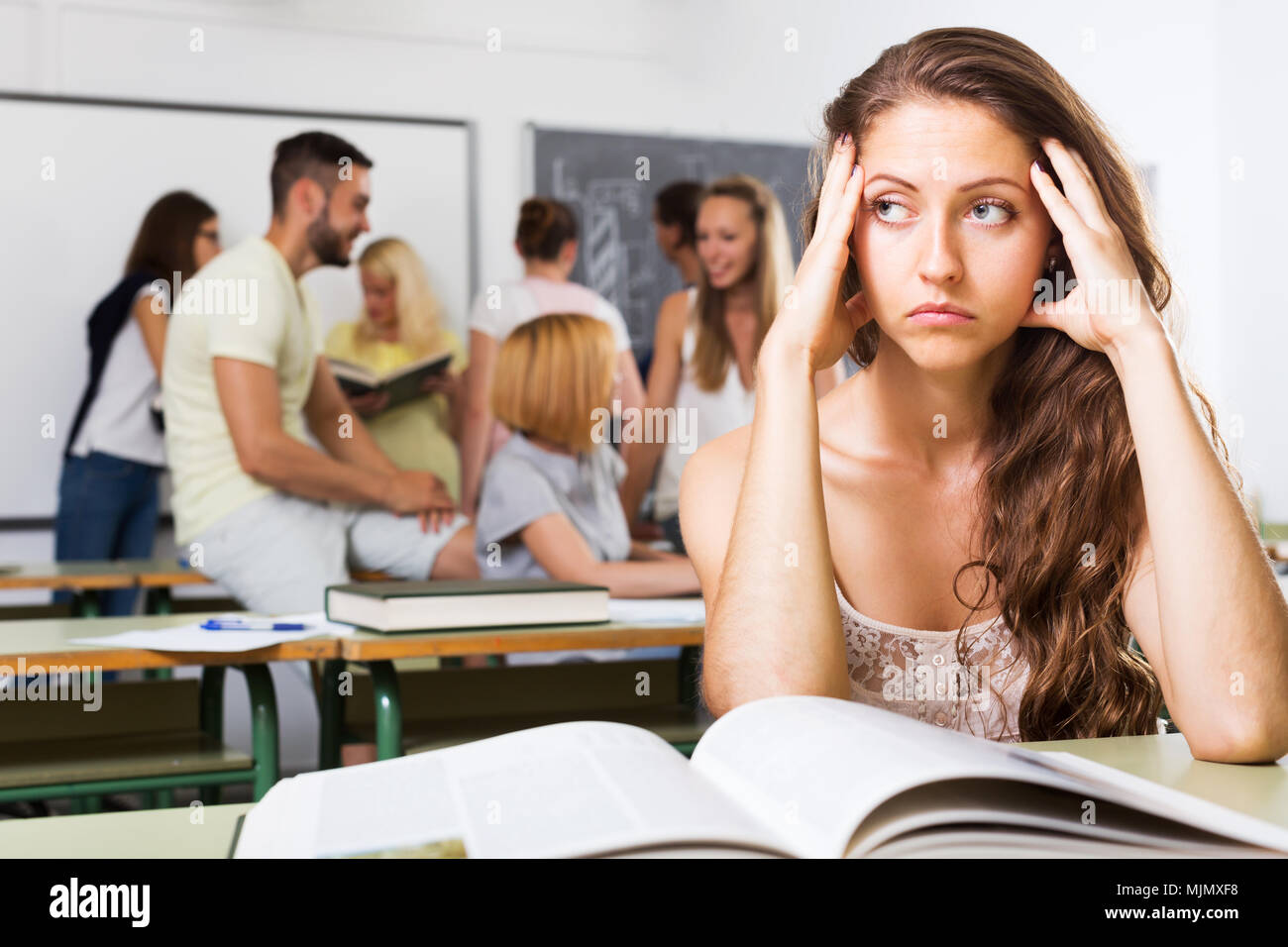 Dejected lonely student with sad expression sits at her desk Stock ...
