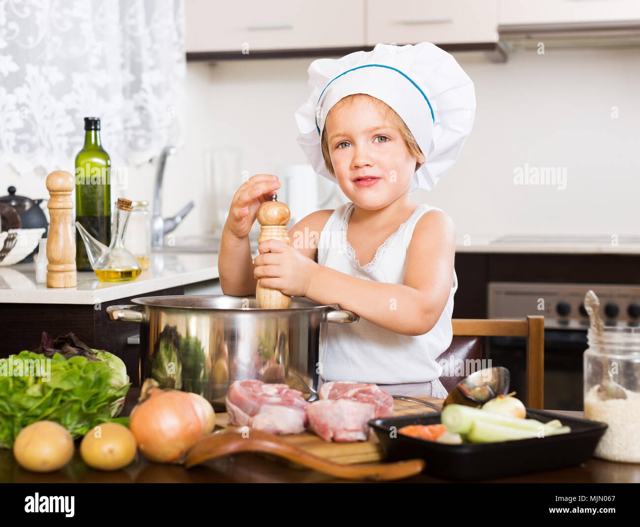 Little girl preparing soup with meat at domestic kitchen Stock Photo ...