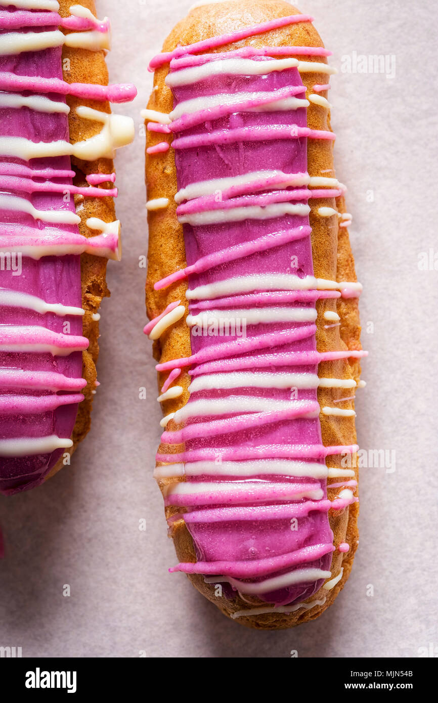 Blackcurrant eclairs. Choux pastries with blackcurrant creme patisserie, topped with ...
