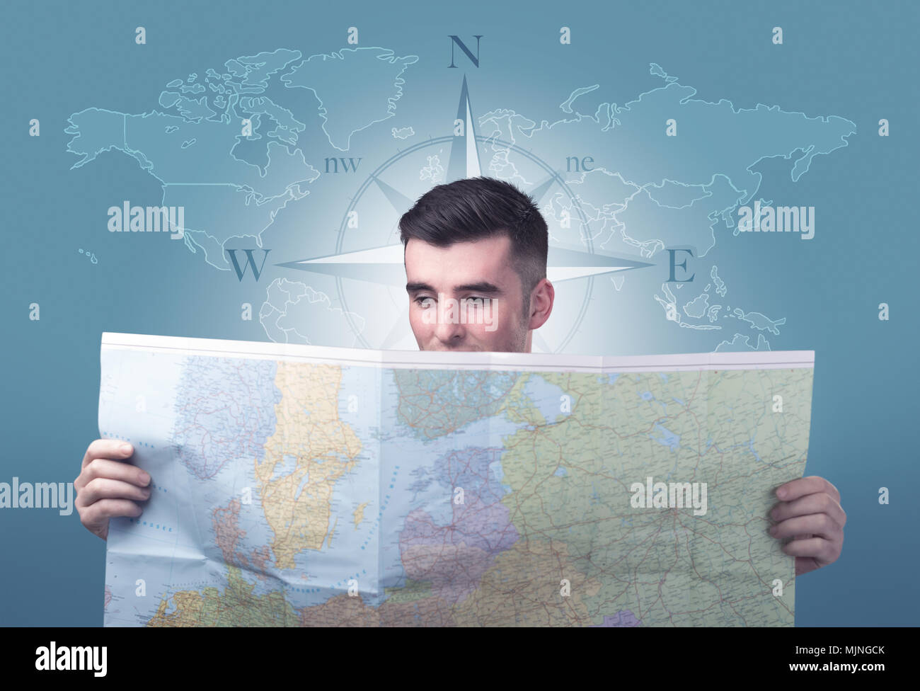Handsome young man holding a map with a world map and a compass behind ...