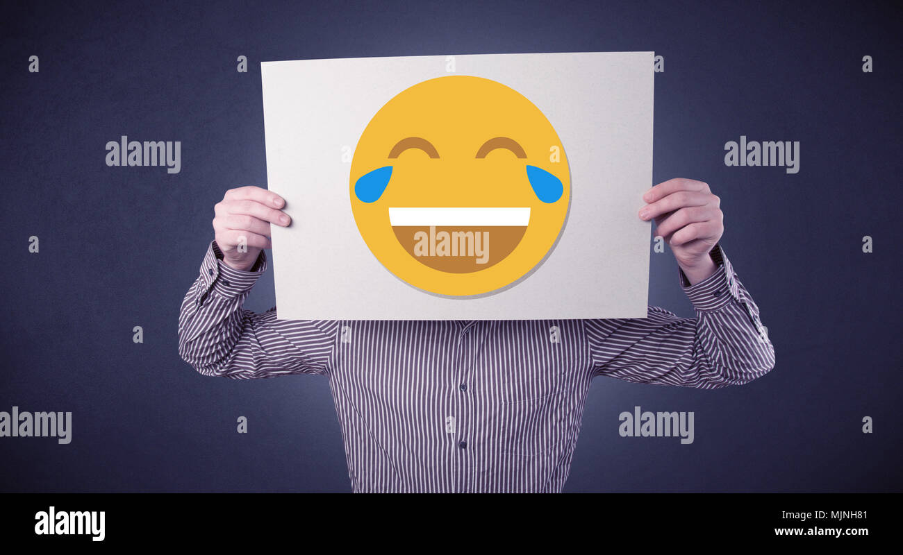 Young businessman hiding behind a laughing emoticon on cardboard Stock ...